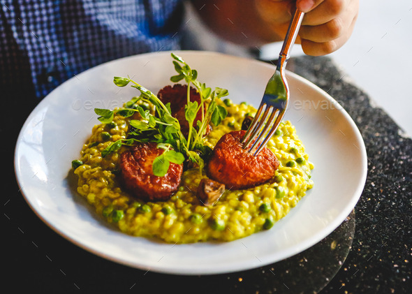 Eating rice and scallops and peas for dinner on a white plate at a high ...