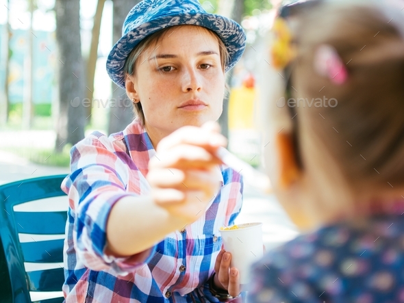 Mom feeds a child with a spoon, family on a walk in the park Stock ...
