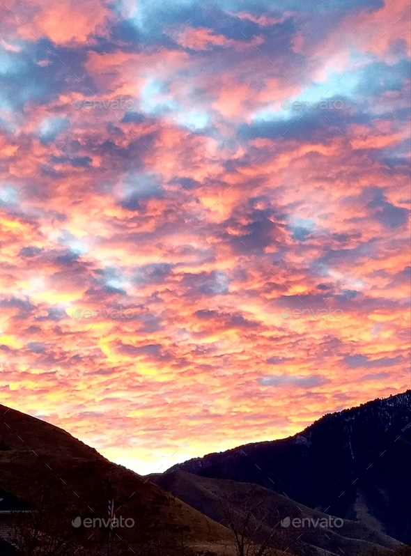 Sherbet colored sky as clouds roll over the mountaintop. Stock Photo by ...