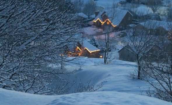 Snow capped rooftops trimmed with Christmas lights glow in the snow ...