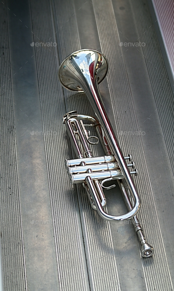 Vertical image of a silver trumpet lying on a football stadium step ...