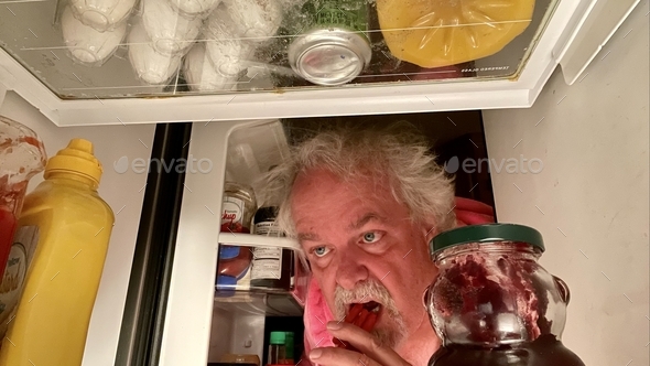 Man in pink bathrobe with bed head looking for snack in empty fridge ...