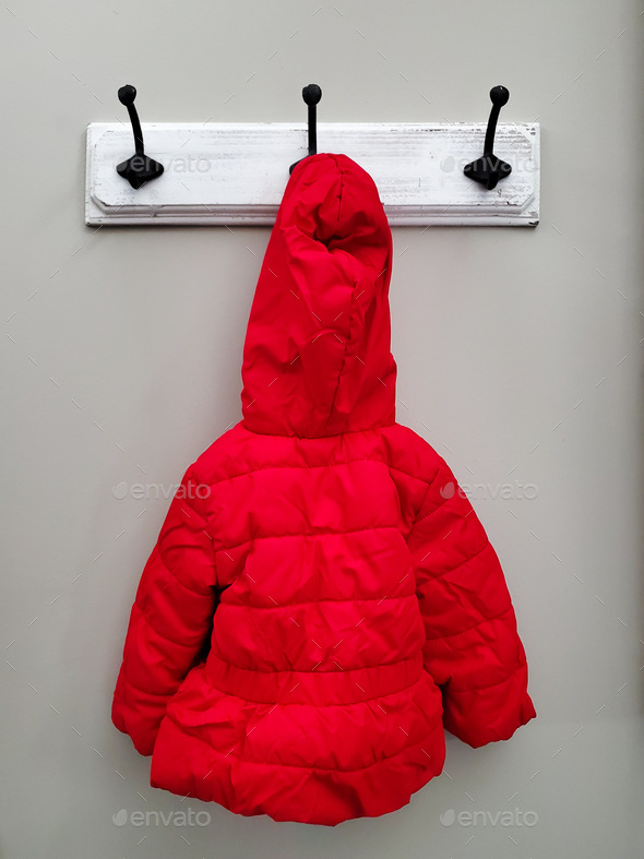 Child’s hooded red winter jacket hanging on a hook on the wall. Stock ...
