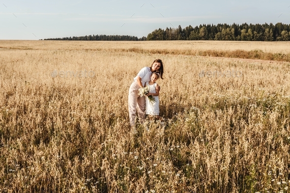 Beautiful young mother and her daughter in field. White clothes ...