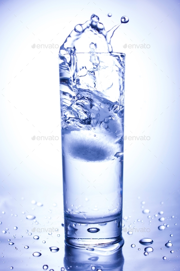 Water splash. Glass of pure water with ice dropped in. Water soluble ...