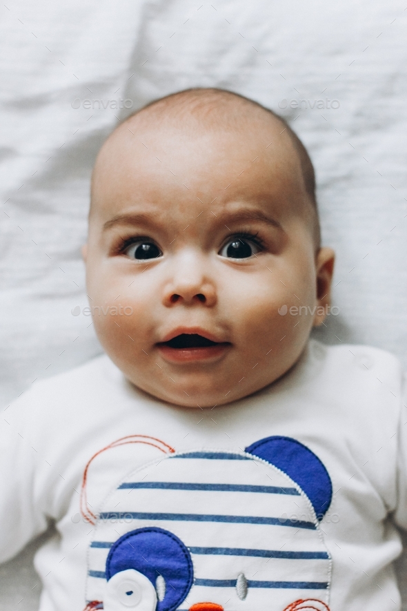 Chubby Cheeky Baby with big eyes on the bed. Happy smiling baby boy ...