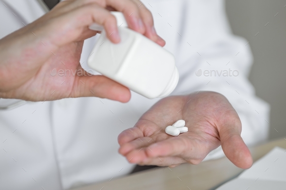 close up hand holds white medication pills. Pour medicine into hand ...