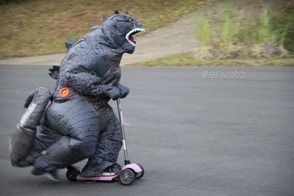 Child in an Inflatable Godzilla Costume on a Scooter Stock Photo by ...