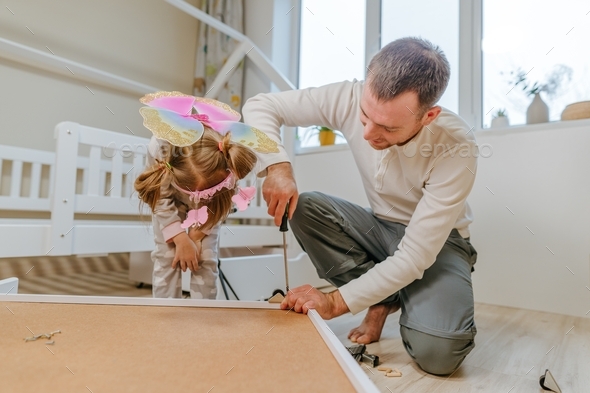 Daddy and daughter having fun time assemble furniture using screw to ...