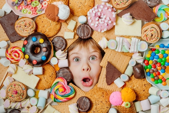 Funny 5 years old girl lying under plenty of sweet foods. Kids face ...