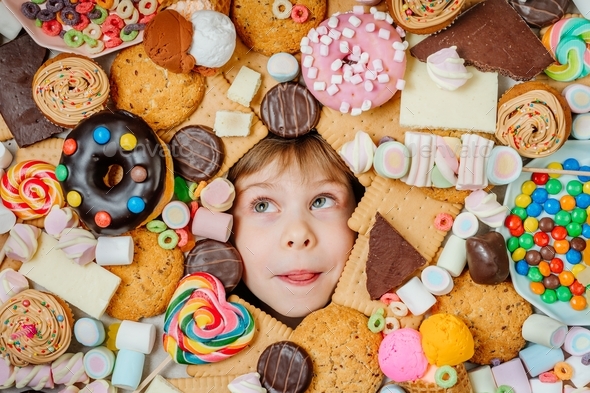 Little girl lying under plenty of sweet foods Stock Photo by lithiumphoto