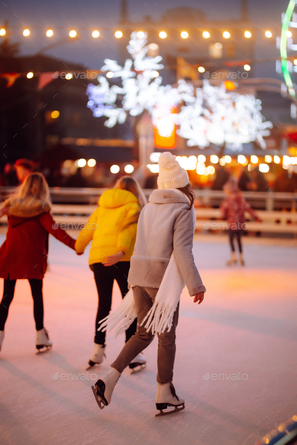Young woman ice skating on ice arena in the city square in winter on ...