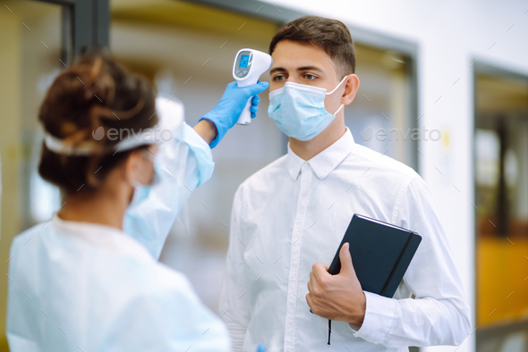 Temperature screening office workers. Disease control expert in visor ...