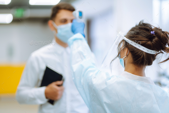 Temperature screening office workers. Disease control expert in visor ...