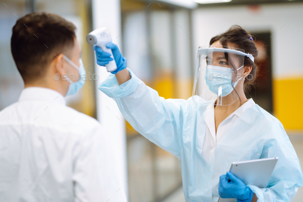 Temperature screening office workers. Disease control expert in visor ...