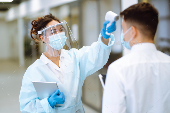 Temperature screening office workers. Disease control expert in visor ...