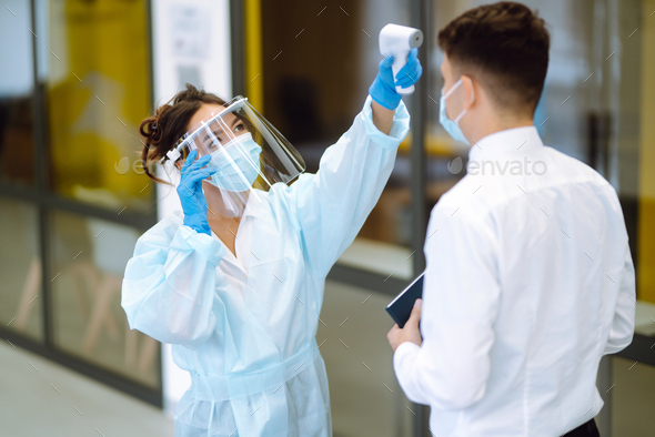 Temperature screening office workers. Disease control expert in visor ...