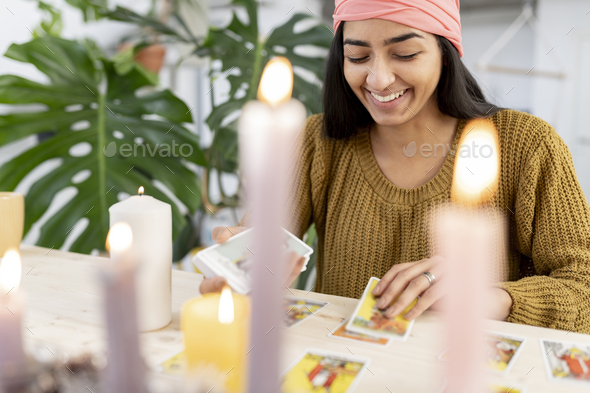 Happy indian woman reading tarot cards with candles at home. Hindu ...