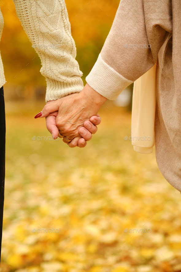 Hands holding together on a natural background Stock Photo by InnaVlasova