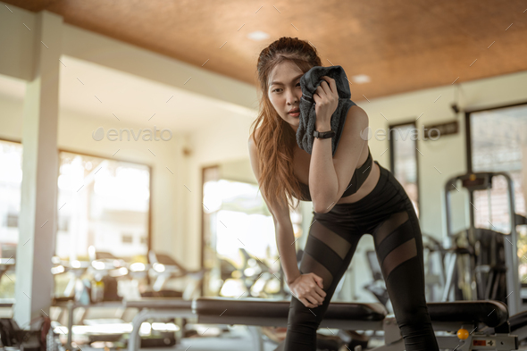 Young woman strand and using towel to wipe the sweat. Relaxation after ...