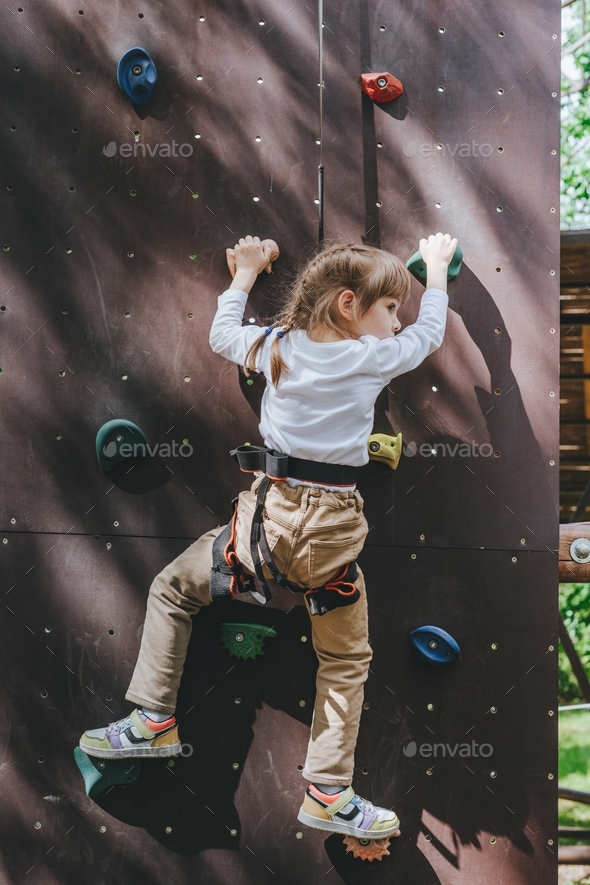 Little girl preschooler climbing on the stand Stock Photo by lithiumphoto