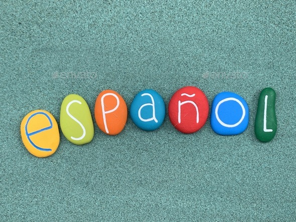 Español word composed with multi colored stone letters over green sand ...