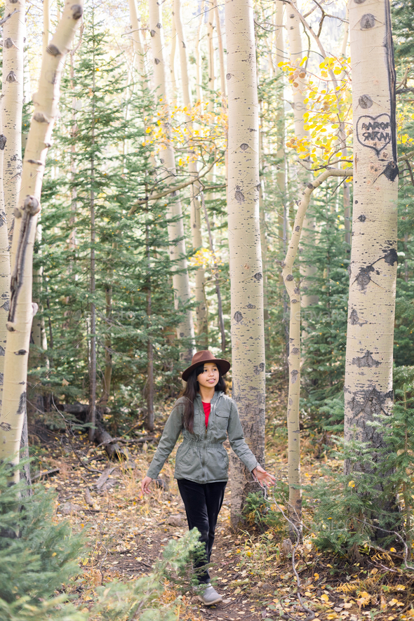 Young girl hiking through tall aspen trees in autumn Stock Photo by ...