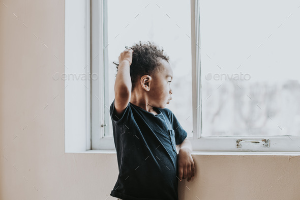 Little boy looking out the window from a room with white walls Stock ...