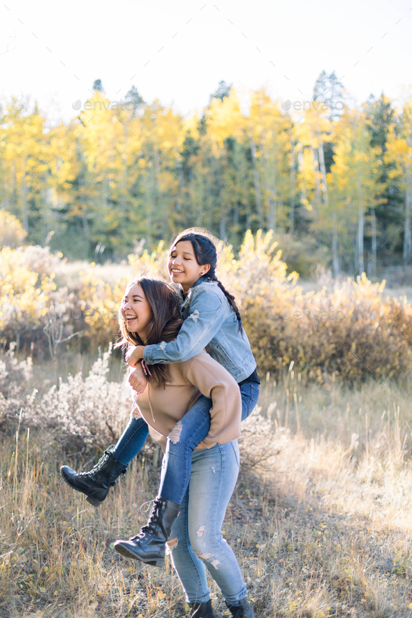 Girl giving a girl a piggyback ride having a great time Stock Photo by ...