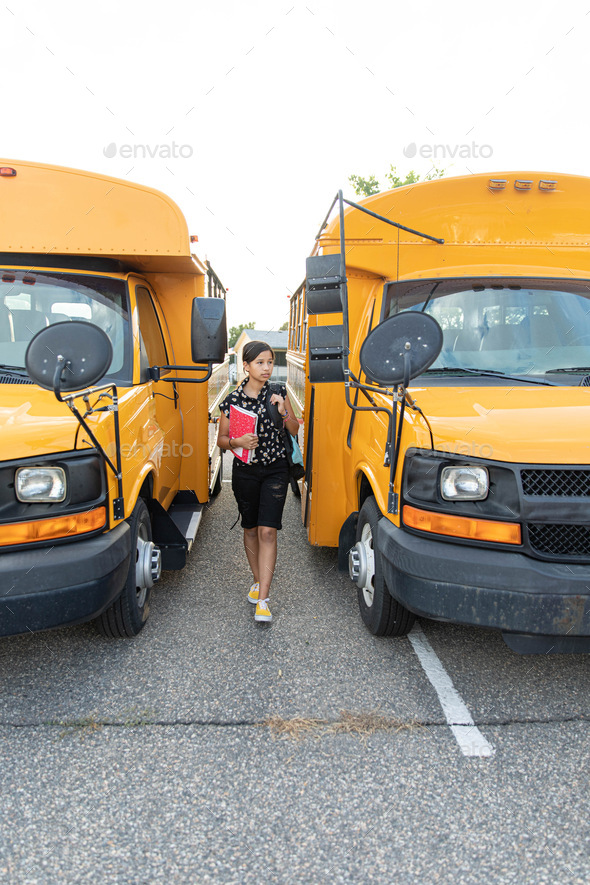 Girl in between school buses going to school Stock Photo by takemewu31