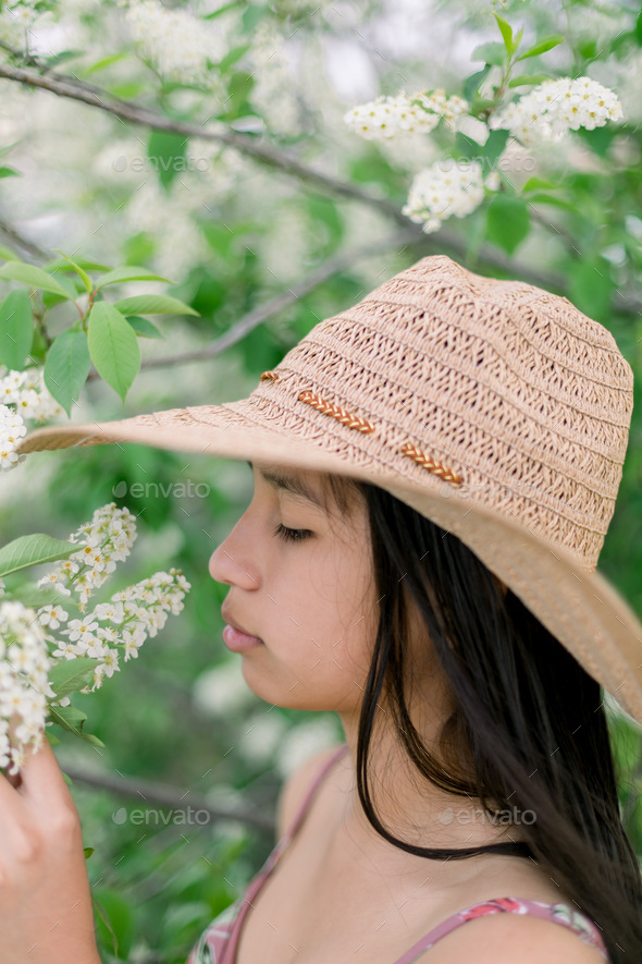 Side view of young girl smelling flowers in spring Stock Photo by ...