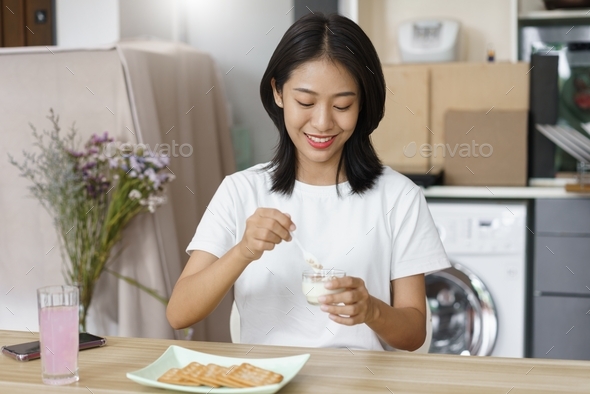 Home relaxation concept, Young woman eating yogurt and crackers for ...