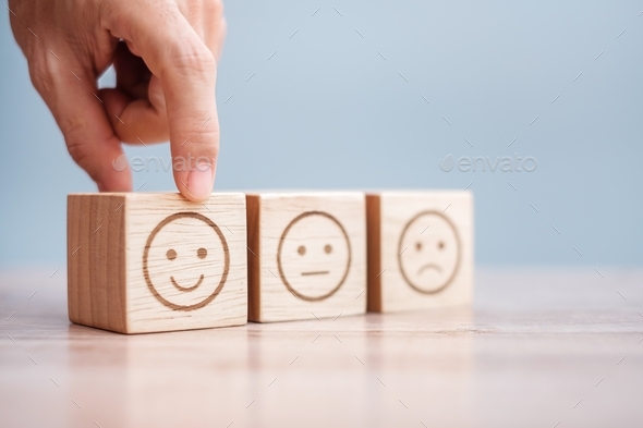 Man hand holding emotion face block. review, satisfaction and feedback ...