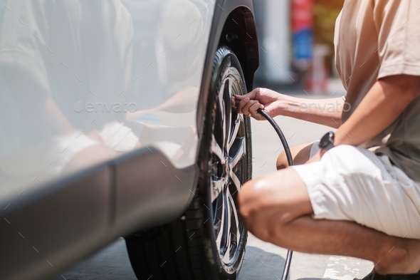 man driver hand inflating tires of vehicle, removing tire valve ...