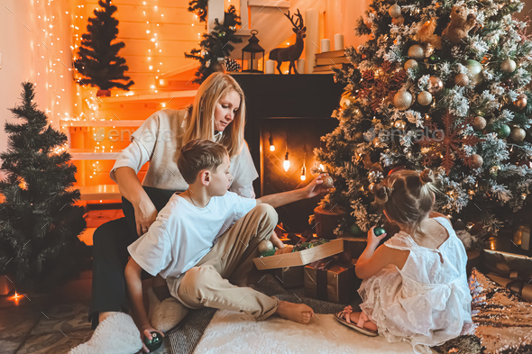Happy family decorating a Christmas tree with boubles and presents in ...