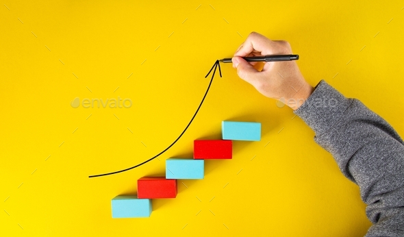 Male hand drawing an upward pointing arrow on top of growing graph made ...
