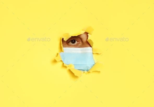 Female face with a face mask peeking out of a hole in paper Stock Photo ...