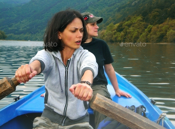 Two young women rowing a boat in the lake Stock Photo by mirarahneva
