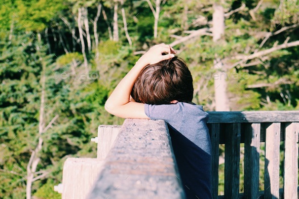 Child leaving on railing with forest background, thoughtful, reflection ...