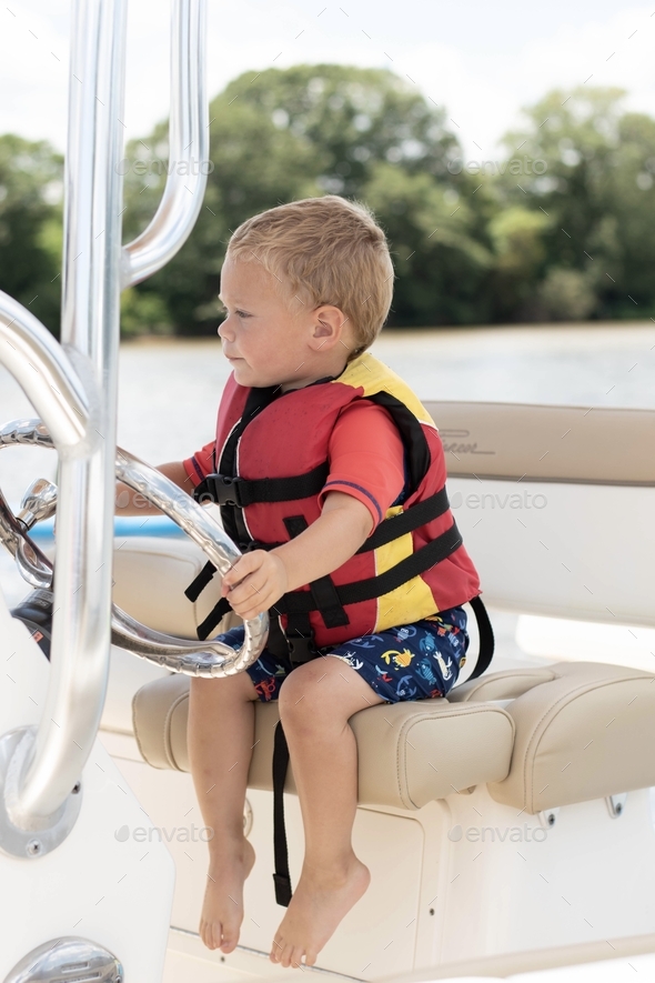Boy in a life jacket steering a boat Stock Photo by ashleyhallphotonnk