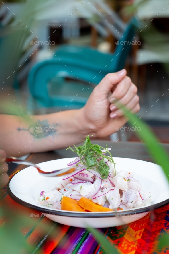 Girl eating fish ceviche. Peruvian food restaurant. Stock Photo by jdvolcan