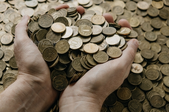 Money background. A full handful of metallic money in hands against the ...