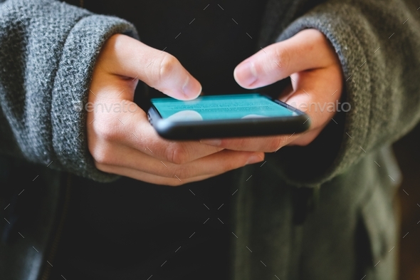 Man with grey jacket on his mobile phone, thumbs typing out a message ...