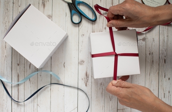 Man wrapping a ribbon on a box to give as a gift. Stock Photo by ...
