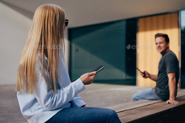 People texting on their mobile phones while keeping the distance due to ...