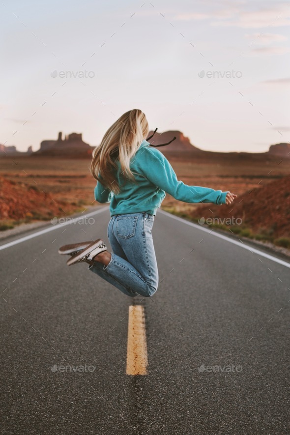 Blonde woman from behind jumping in front of monument valley Stock ...