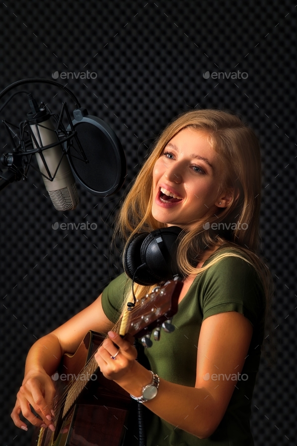 Attractive female singing and playing guitar and singing in dark room ...