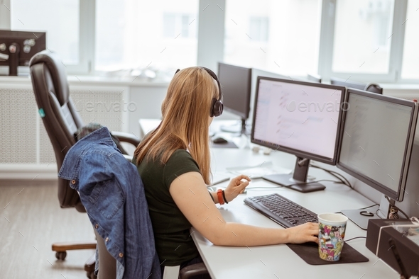 Women in the office working and looking to the computer monitors ...