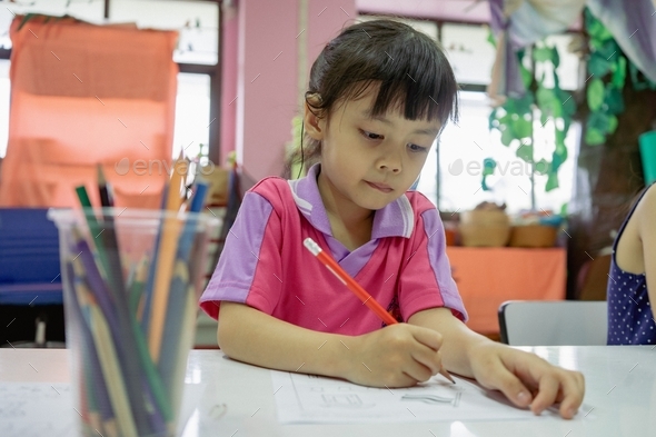 Student sit and write on table in classroom Stock Photo by Karunyapas