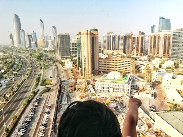 Child from behind points at the city view from his apartment building ...